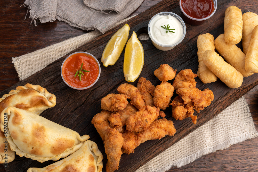 Picada board with nugget empanadas and tequeños with lemon slices and ...