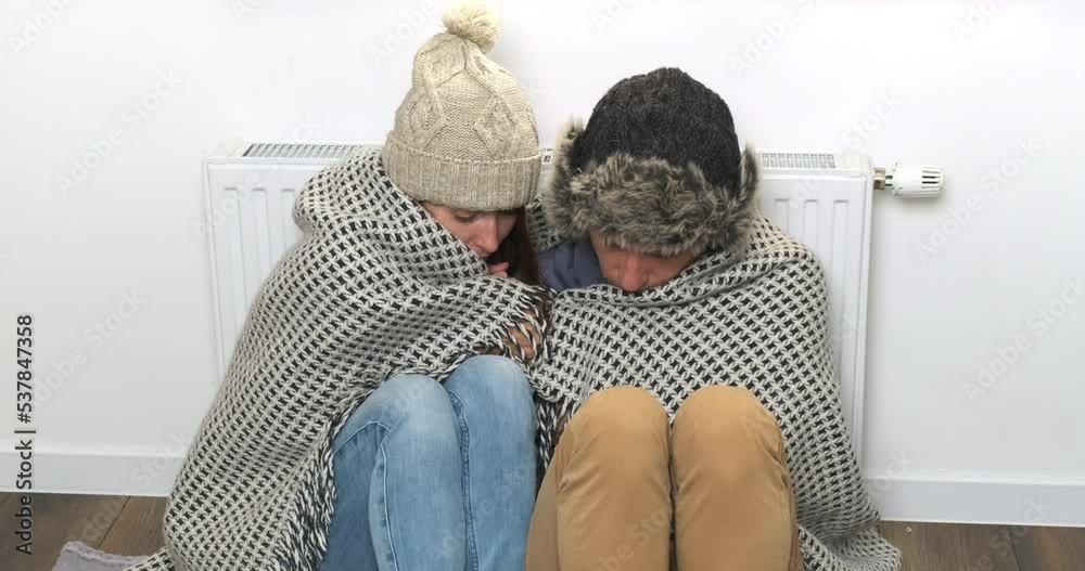 Man and woman shaking, shivering in cold room, sitting near battery ...