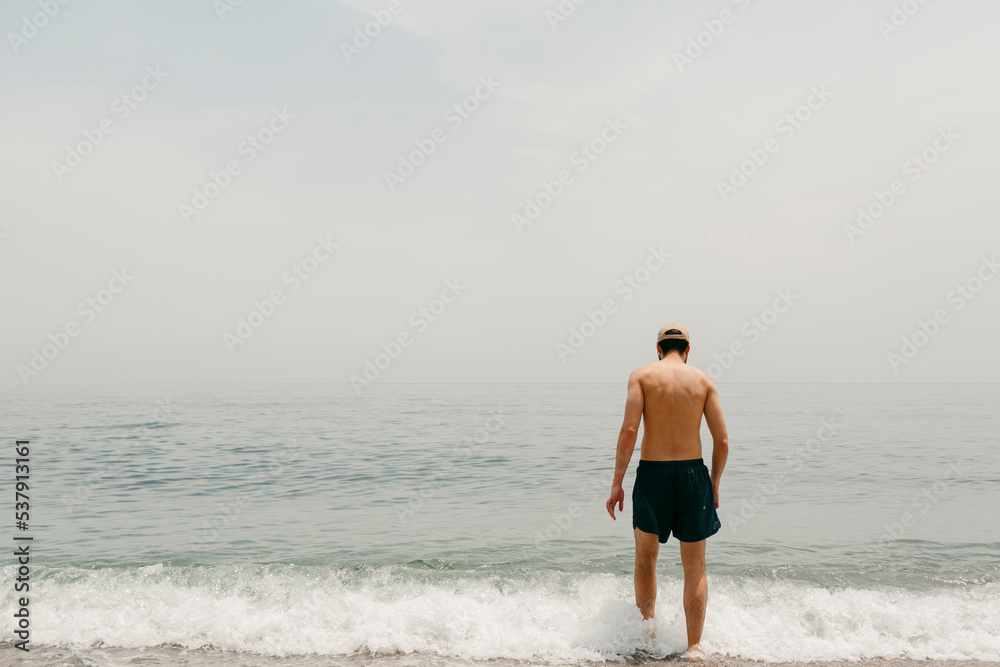 Back of man in swimwear on the shoreline of Mediterranean Sea foto de ...