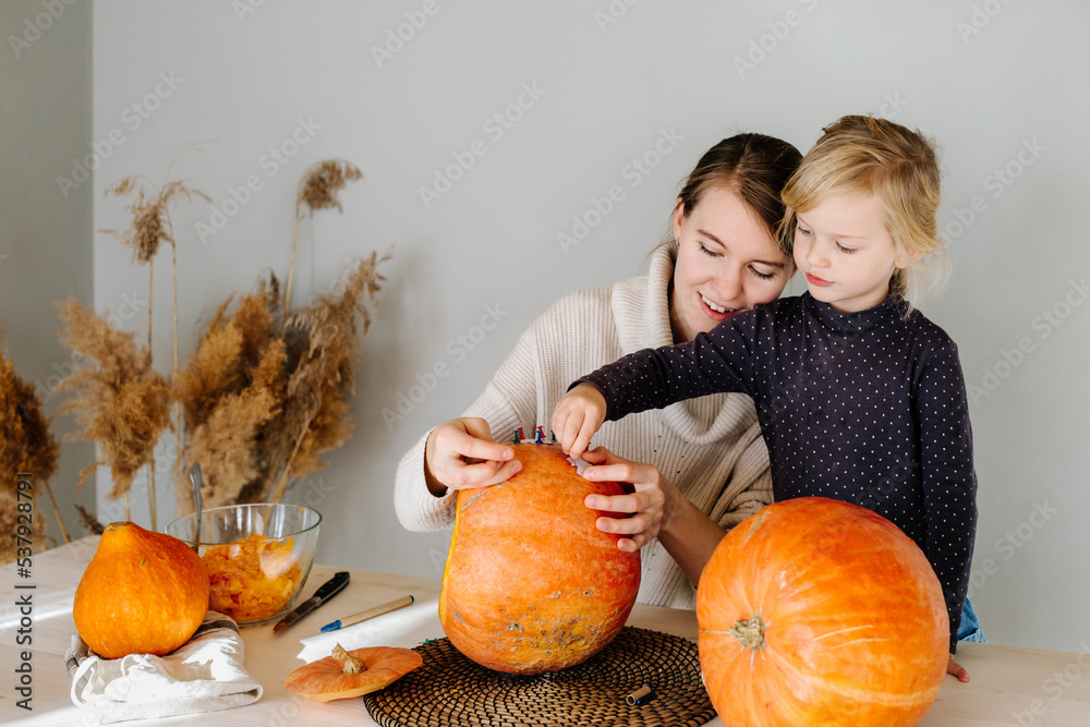 Mother and daughter attaching stencil to pumpkin Stock Photo | Adobe Stock