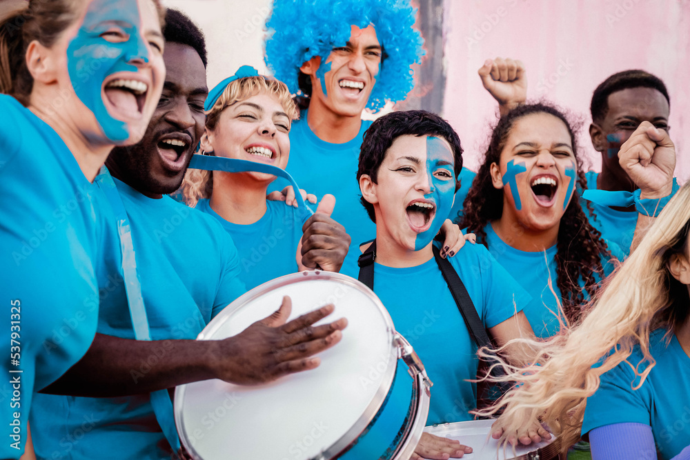 Multiracial football fans celebrating in crowd while watching game at ...