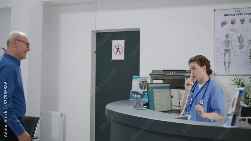 Woman nurse answering landline phone call at reception desk in ...