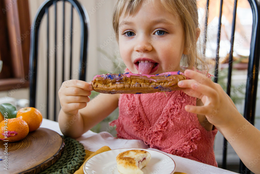 Cute girl eating eclair Stock Photo | Adobe Stock
