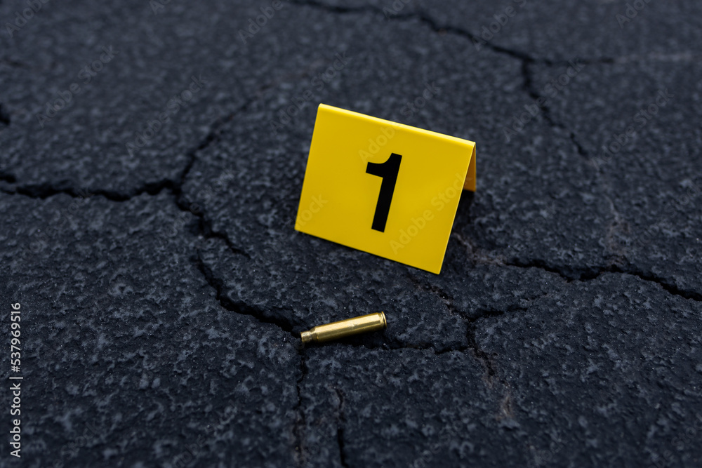 One yellow crime scene evidence marker on the street after a gun ...