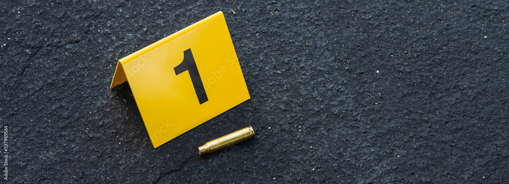 One yellow crime scene evidence marker on the street after a gun ...