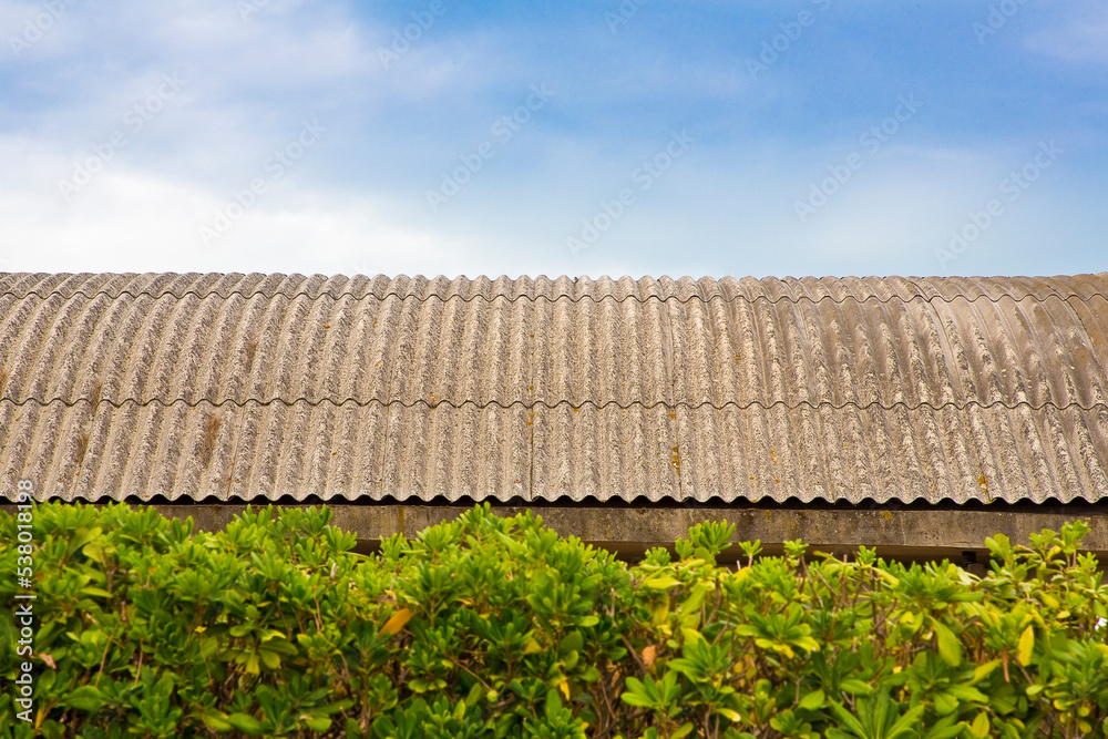 Old aged dangerous roof made of corrugated asbestos panels with curved ...