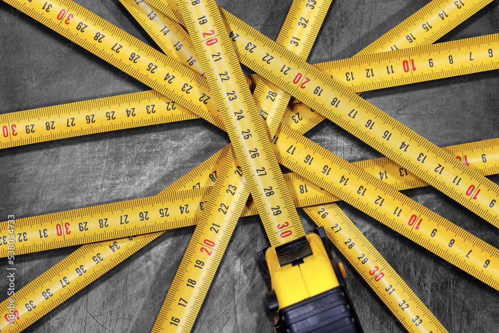 Large group of yellow and orange tape measures on a silver metal ...