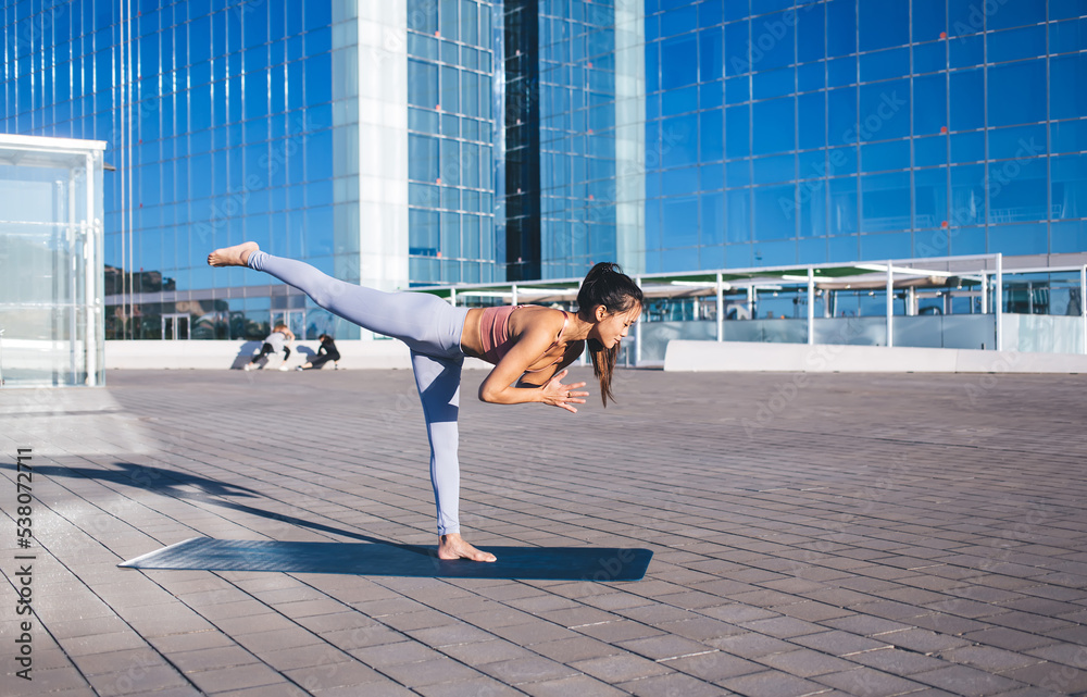 Flexible woman practice balance asana with raising leg breathing at ...