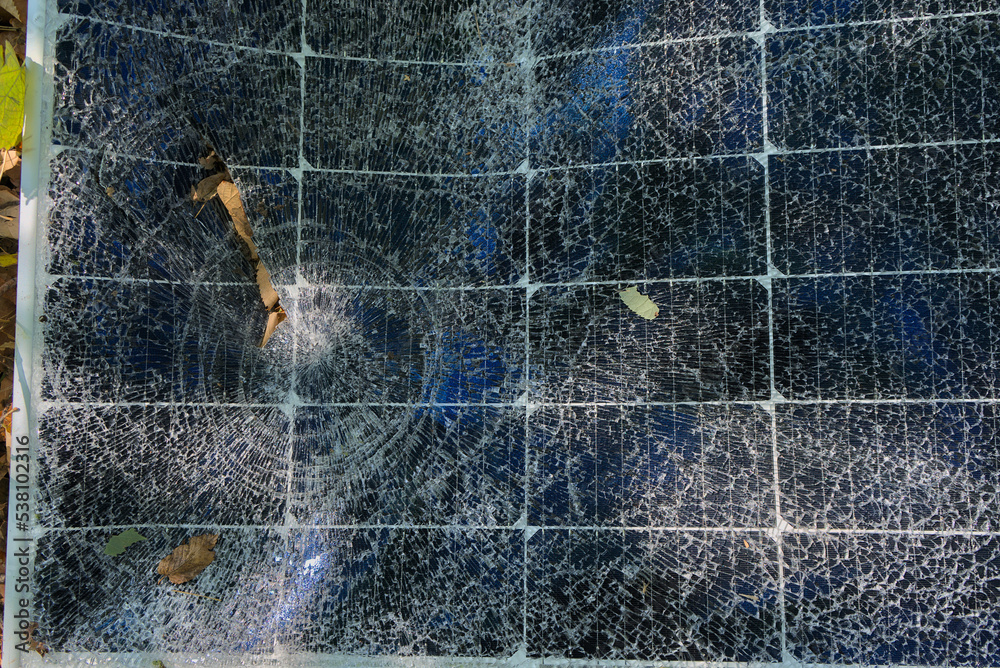 A broken solar panel, a torn panel mount lie on the ground ...