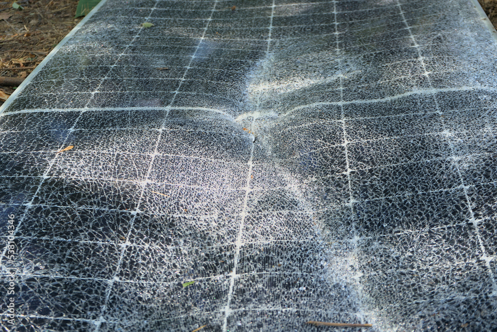 A broken solar panel, a torn panel mount lie on the ground ...