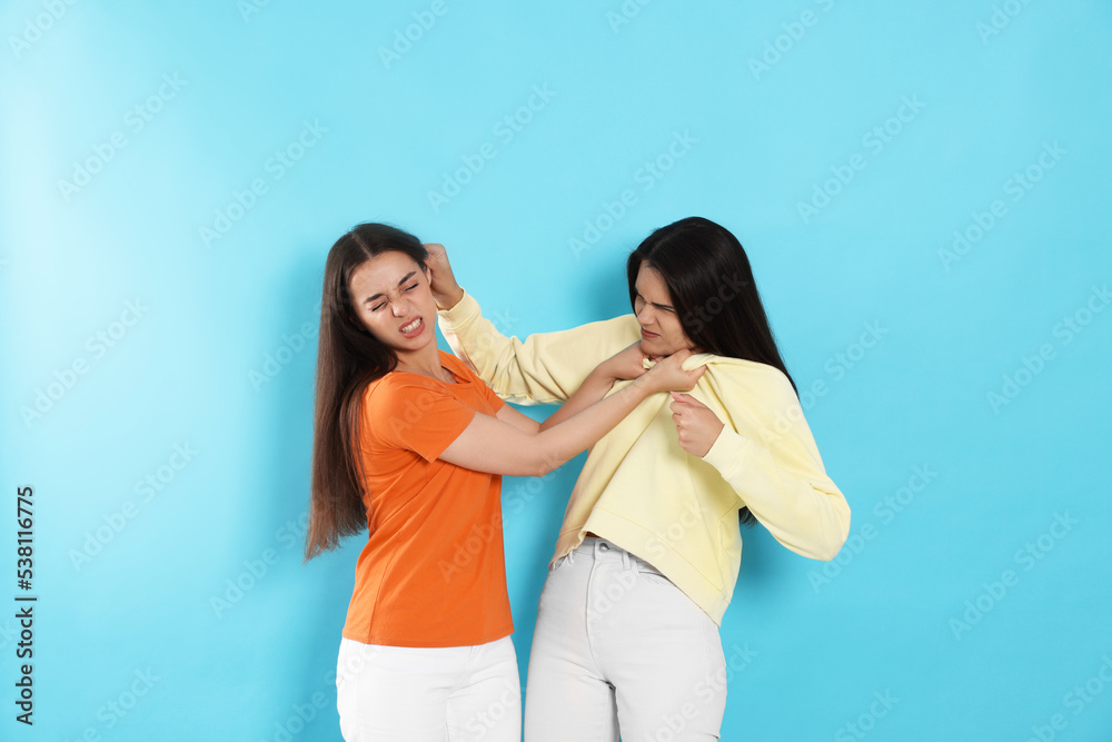 Aggressive young women fighting on light blue background Stock Photo ...