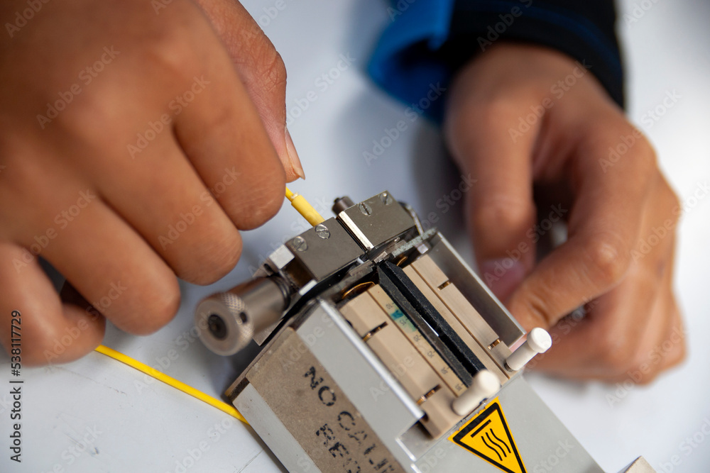 Technician cleaving an optical fiber, a crucial process for a good fusion of optical fibers ...