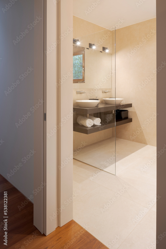 Modern bathroom front view with large light marble slabs. There are two ...