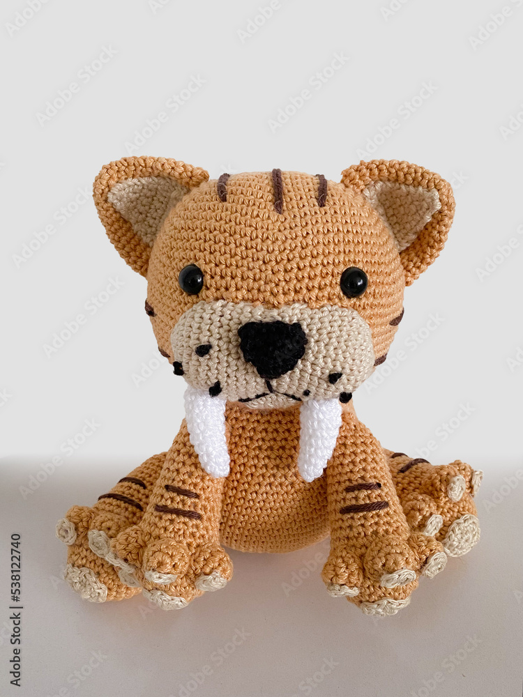 Light brown saber-toothed tiger on white background. Amigurumi toy ...