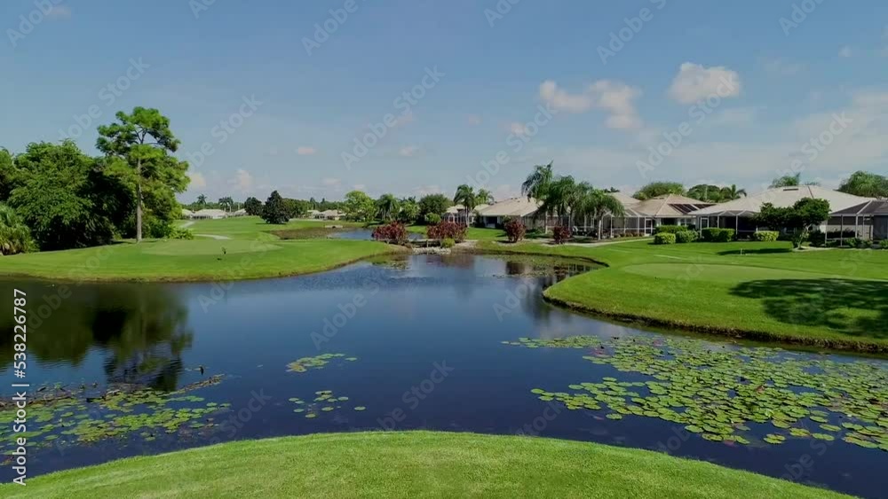 Drone flyover from the grass over water in a golf course field with ...