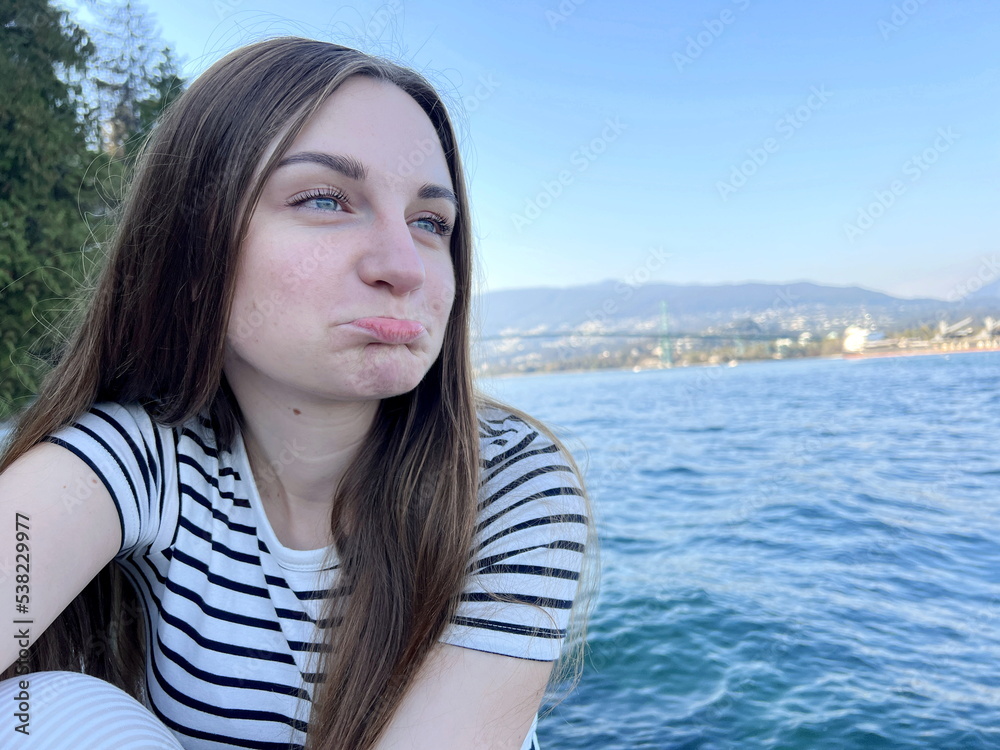 young woman on ocean is sad Close-up of her face she playfully pouts ...