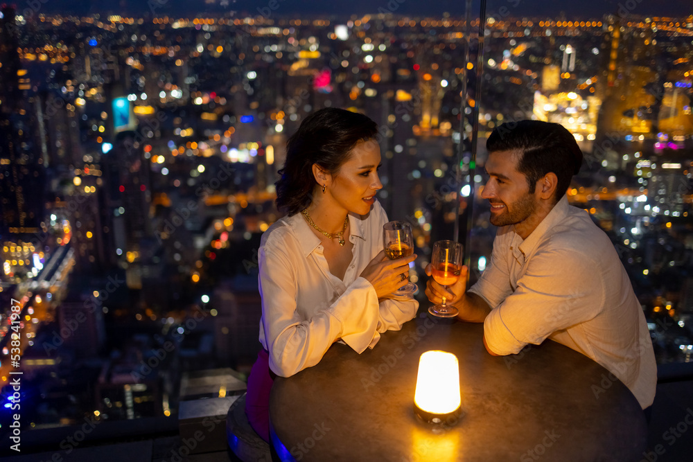 Caucasian couple celebrating holiday event at luxury skyscraper rooftop ...
