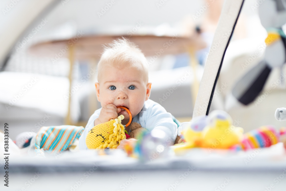Cute baby boy playing with hanging toys arch on mat at home Baby ...