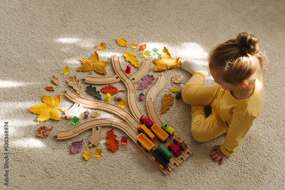 A little girl playing with autumn leaves and make a tree with wooden ...