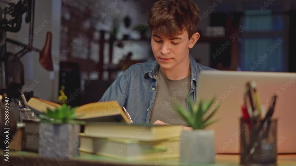 Teenage student learning at home with books and laptop computer. Online ...