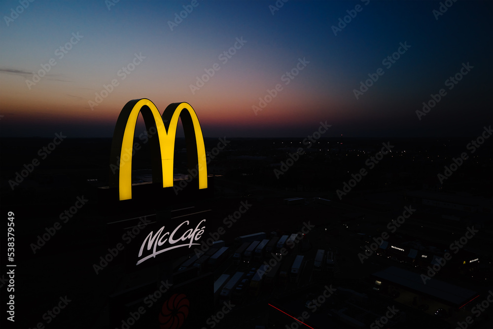 Glowing McDonalds restaurant sign against night sky. Logo of McCafe ...