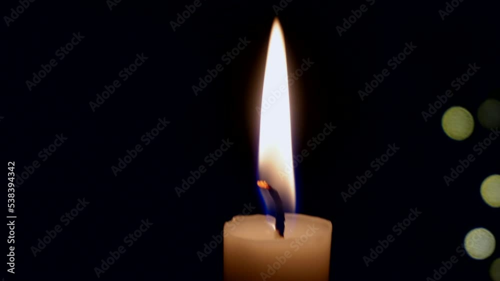 A single candle burns. Close-up of a white wax candle in the dark ...