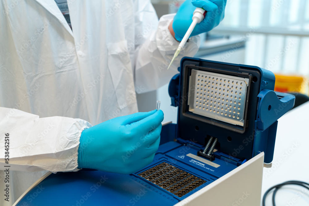 Loading a DNA tube into a PCR (polymerase chain reaction) thermocycler ...