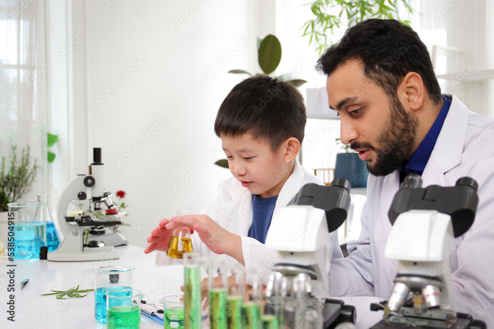 Lovely Asian young boy in lab coat enjoy doing an experiment and ...