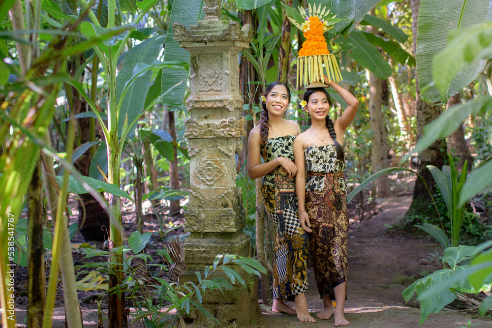 Two Bali woman clothing kebaya with a batik kamben in front of Hindu ...