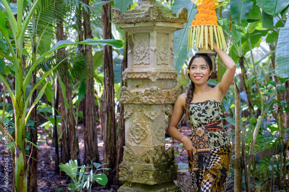 Young Bali woman clothing kebaya with a batik kamben in front of Hindu ...