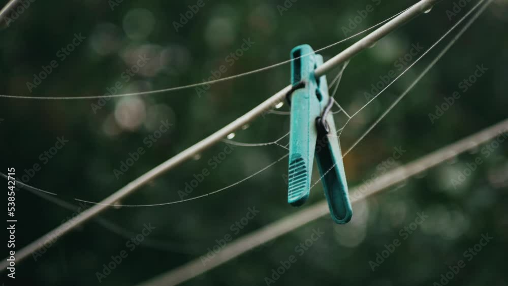 green clothespin with web threads hanging on a wire, clothespin close ...