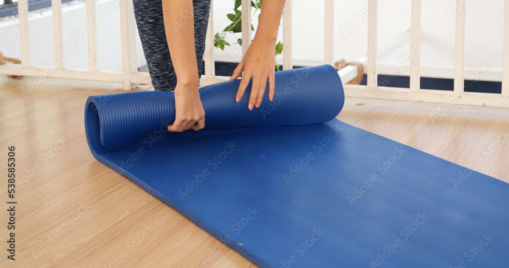 Woman hands rolled up yoga mat on gym floor in yoga fitness training ...