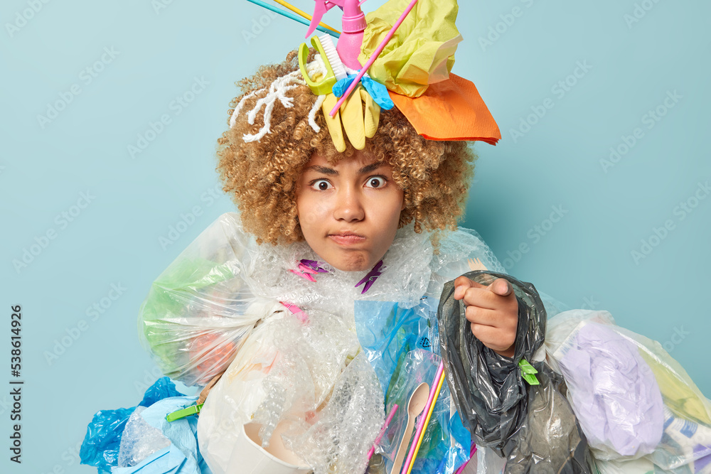 Strict displeased woman wears garbage costume points index finger ...