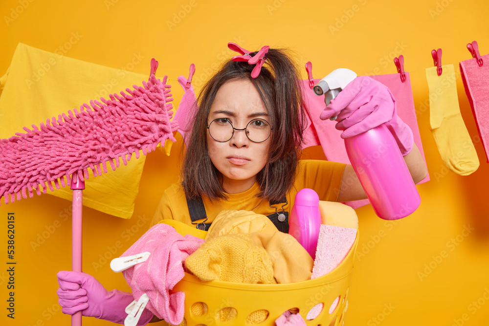 Serious busy Asian woman with dark hair holds cleaning mop and ...