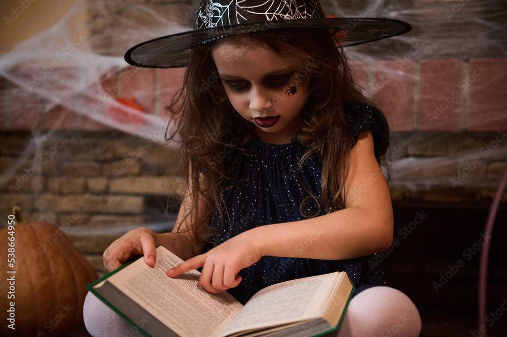 Little girl, sorceress in a witch carnival costume and wizard hat, with ...