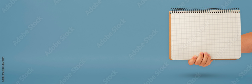 Notepad in hand. Blank notepad in the hands on a blue background. Hands ...