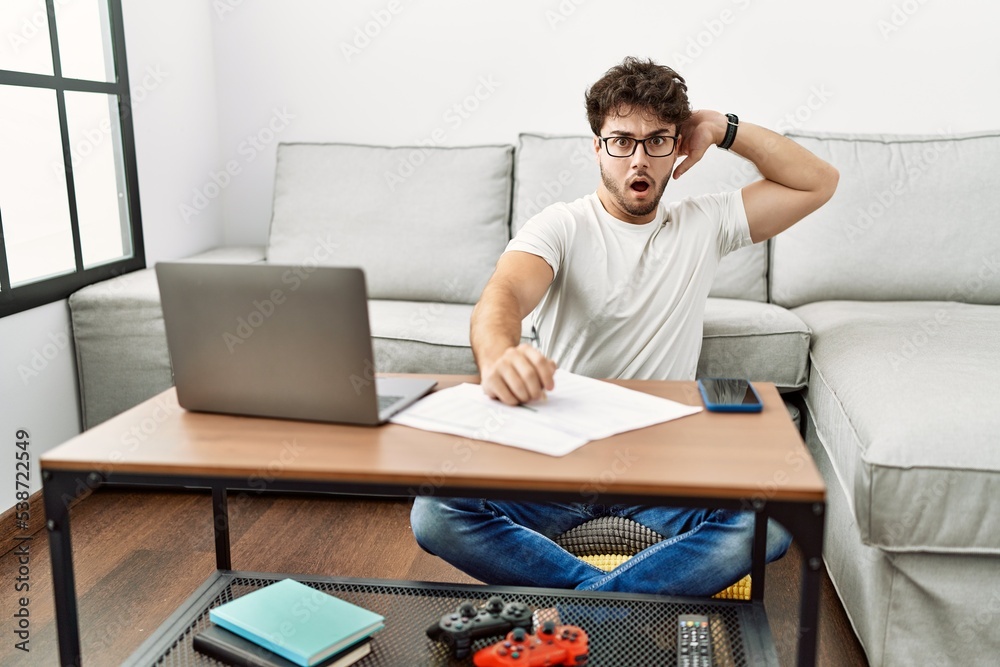 Hispanic man doing papers at home crazy and scared with hands on head ...