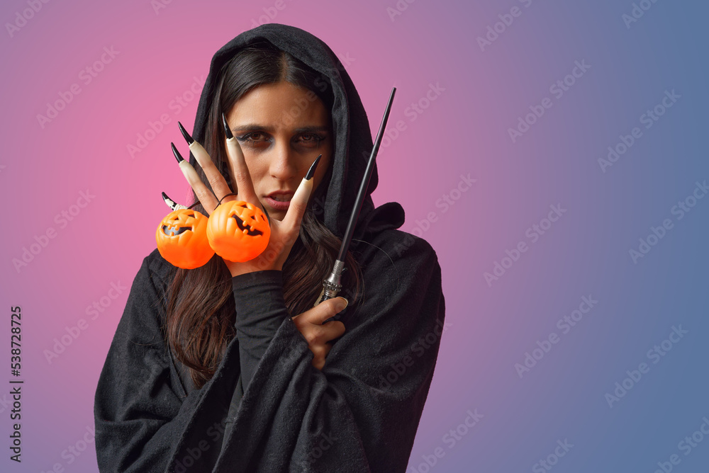 Evil mysterious witch holding symbols of halloween - jack o lantern and ...