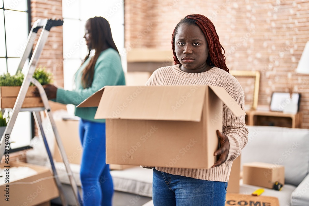 Foto de Two african women moving to a new home depressed and worry for ...