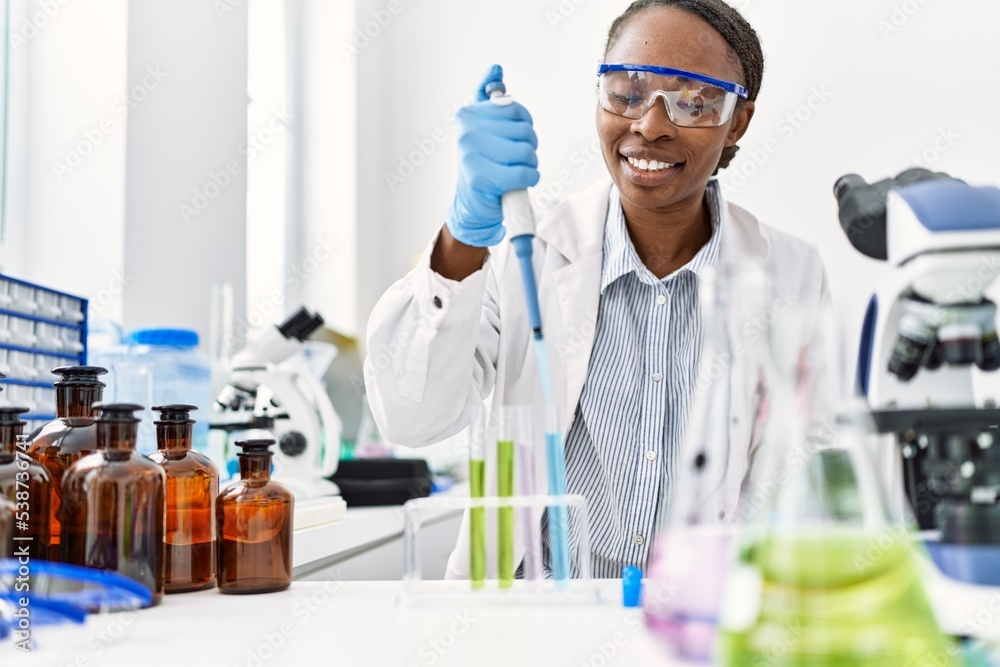 African american woman scientist pouring liquid on test tube at ...