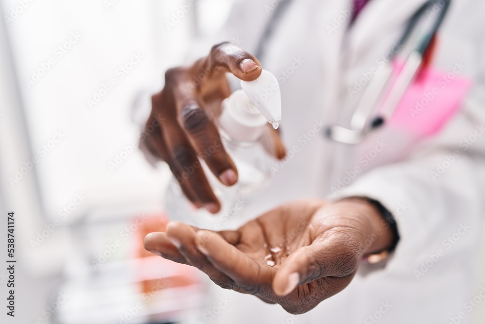 African american woman wearing doctor uniform using sanitizer gel hands ...