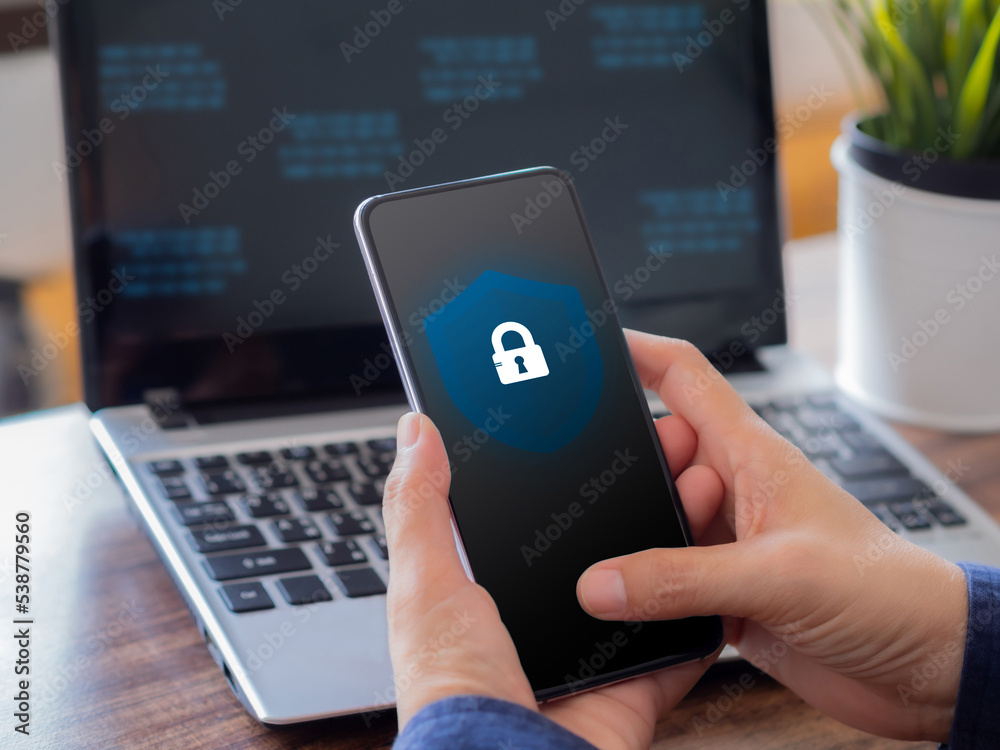 Hand-holding smartphone showing padlock icon on screen authentication on office table. Security ...