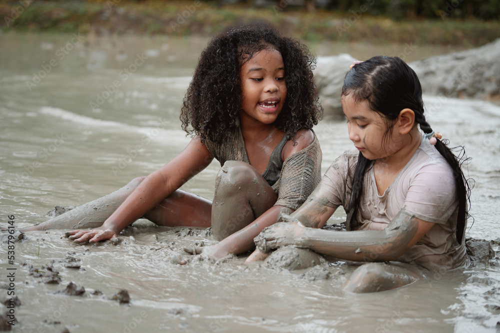 Group of happy children girl playing in wet mud puddle during raining ...