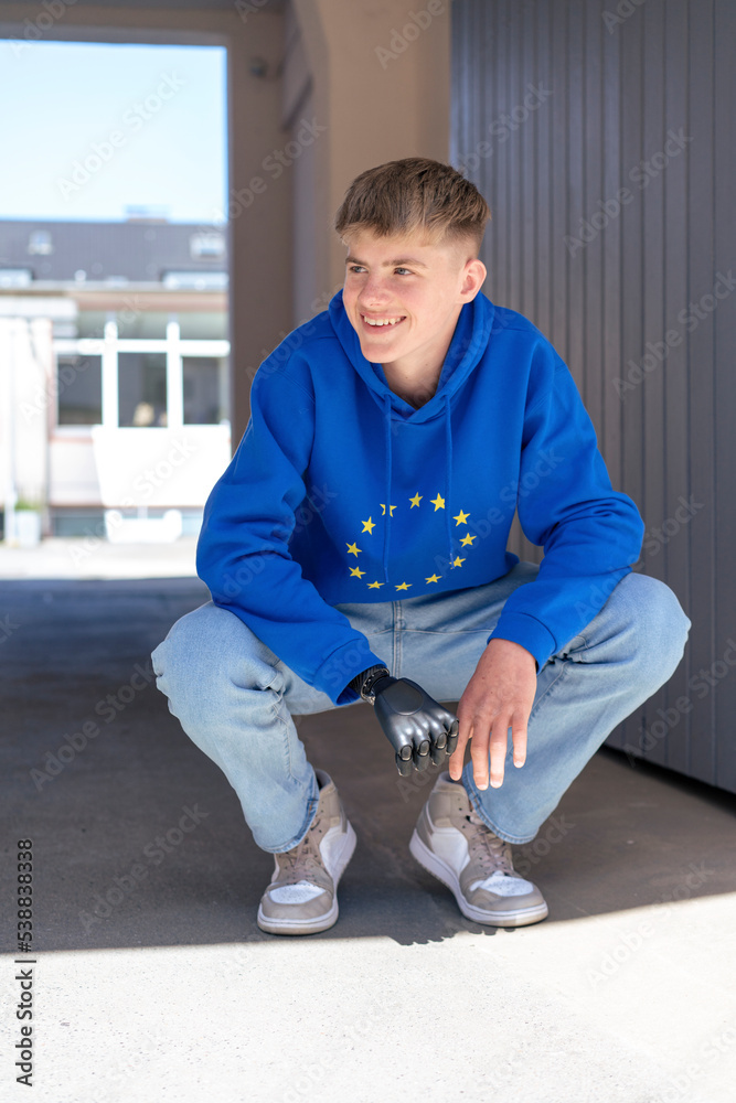 Smiling boy with prosthetic arm crouching under shadow Stock Photo ...