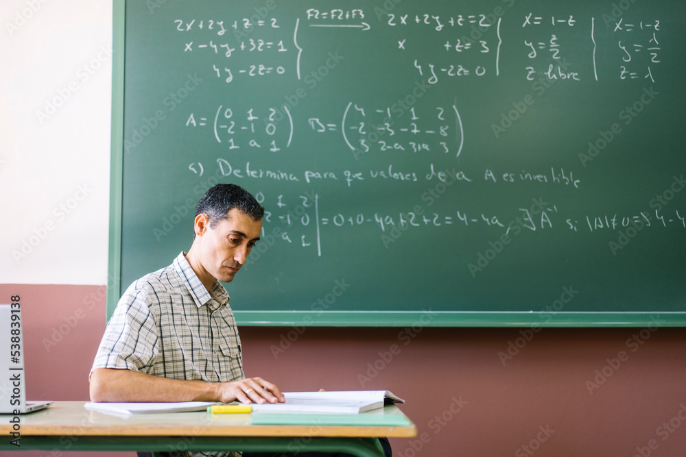 Math teacher reading book in classroom Stock Photo | Adobe Stock
