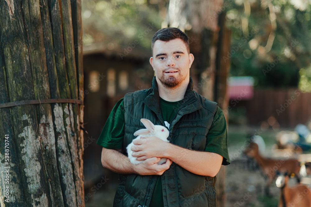 Caretaker with down syndrome taking care of animals in zoo, stroking ...