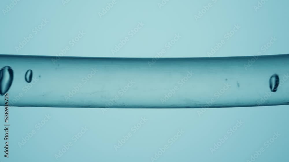 Macro shot of different sized clear bubbles flowing in glass tube with ...