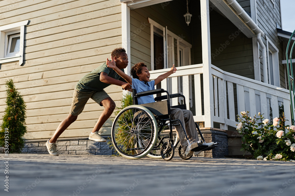 Fotka „Side view portrait of black teenage boy pushing littlle brother ...