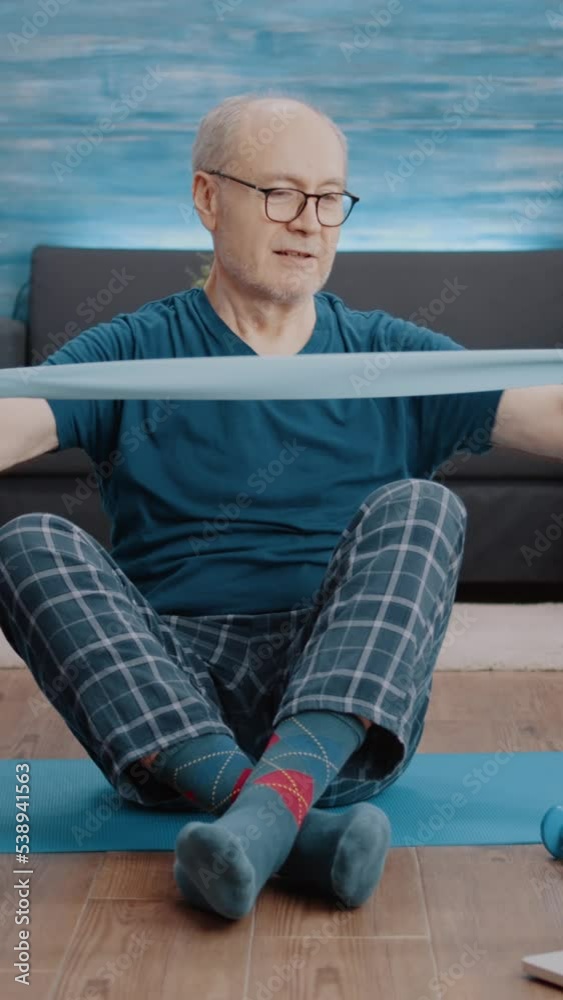 Vidéo Stock Vertical video: Senior person pulling flexible resistance ...