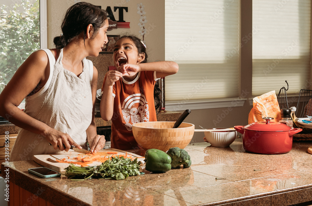 Cooking with Mom and daughter while laughing together in the kitchen ...